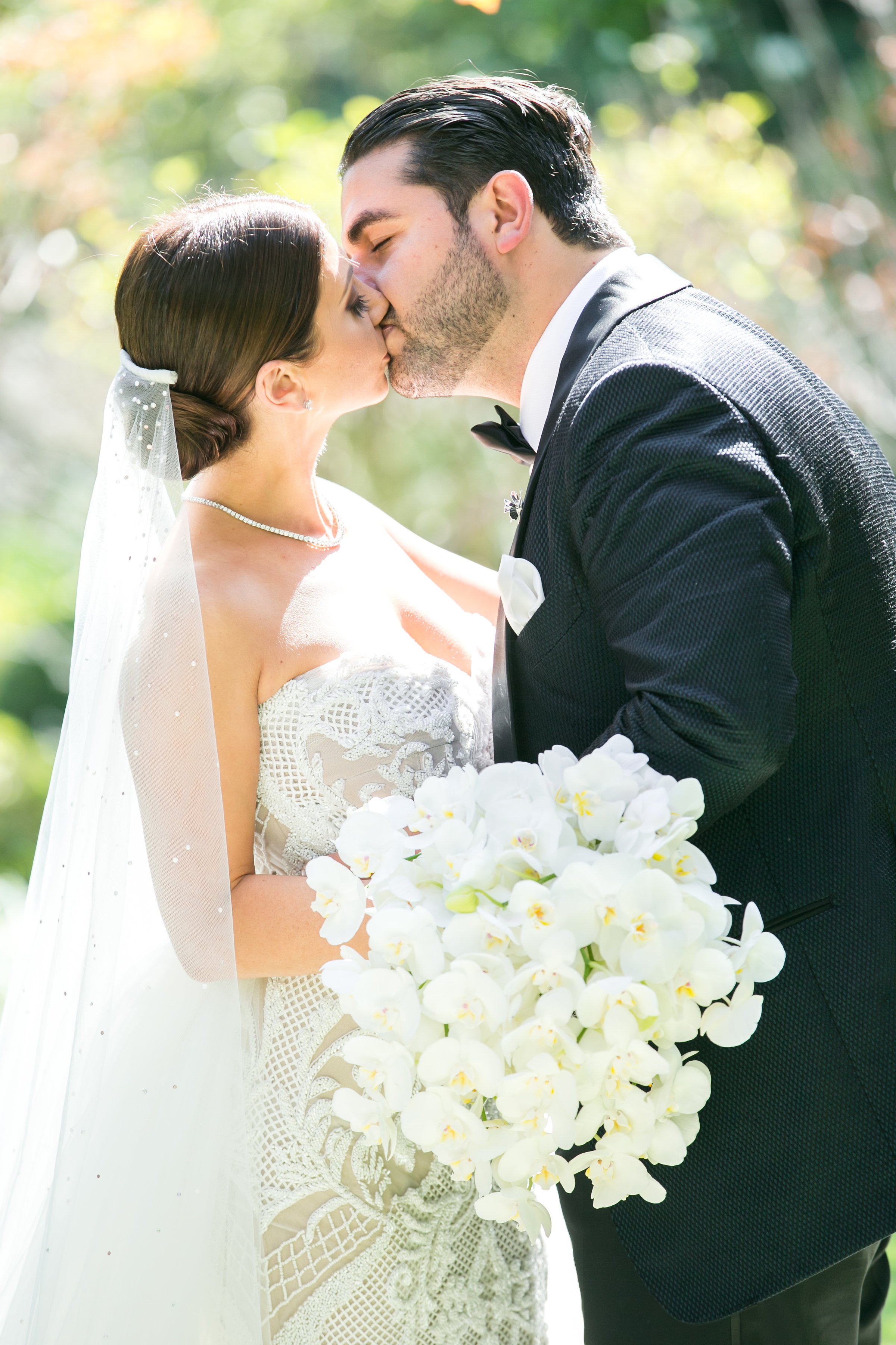 Bride with Orchid Bouquet Kisses Groom