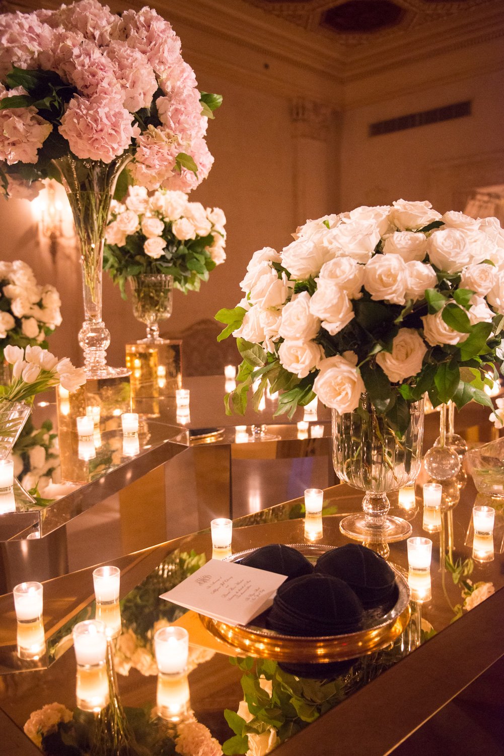 Yarmulkes on Reflective Table with Candles and Flowers
