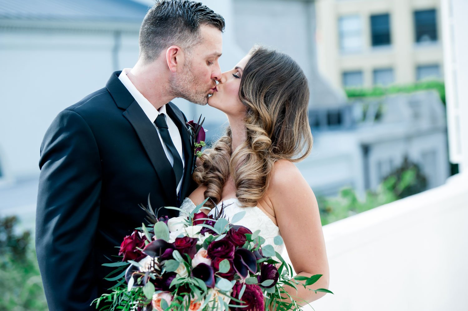 Bride with Burgundy Bouquet Kissing Groom