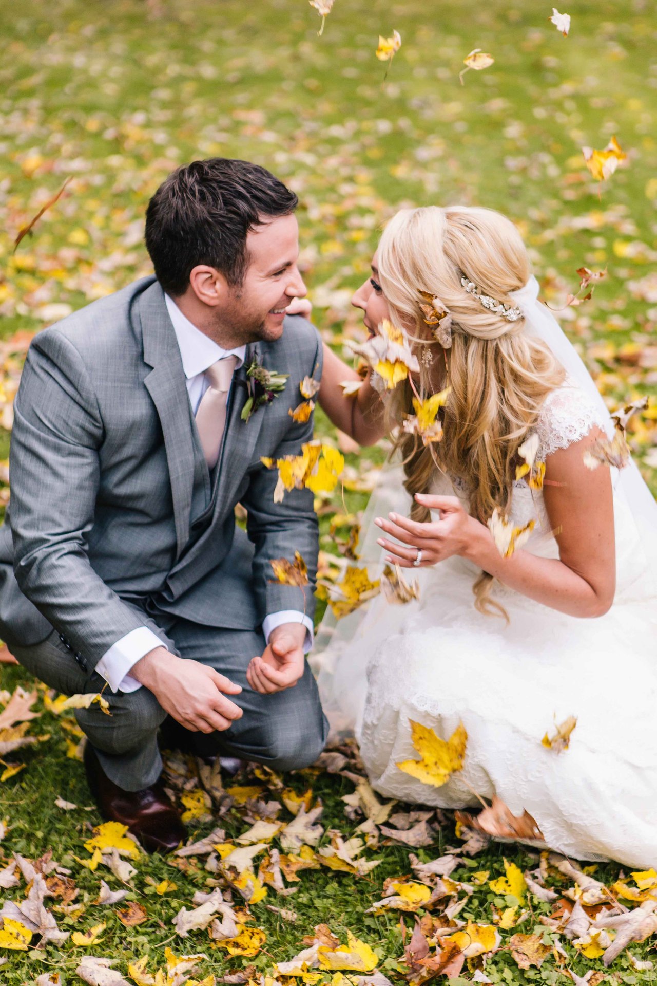 Bride and Groom Kneel in Fall Leaves